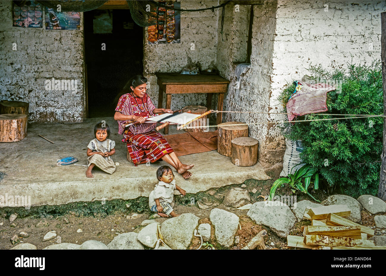 Young Mam Mayan mother using a backstrap loom on the porch of her home ...