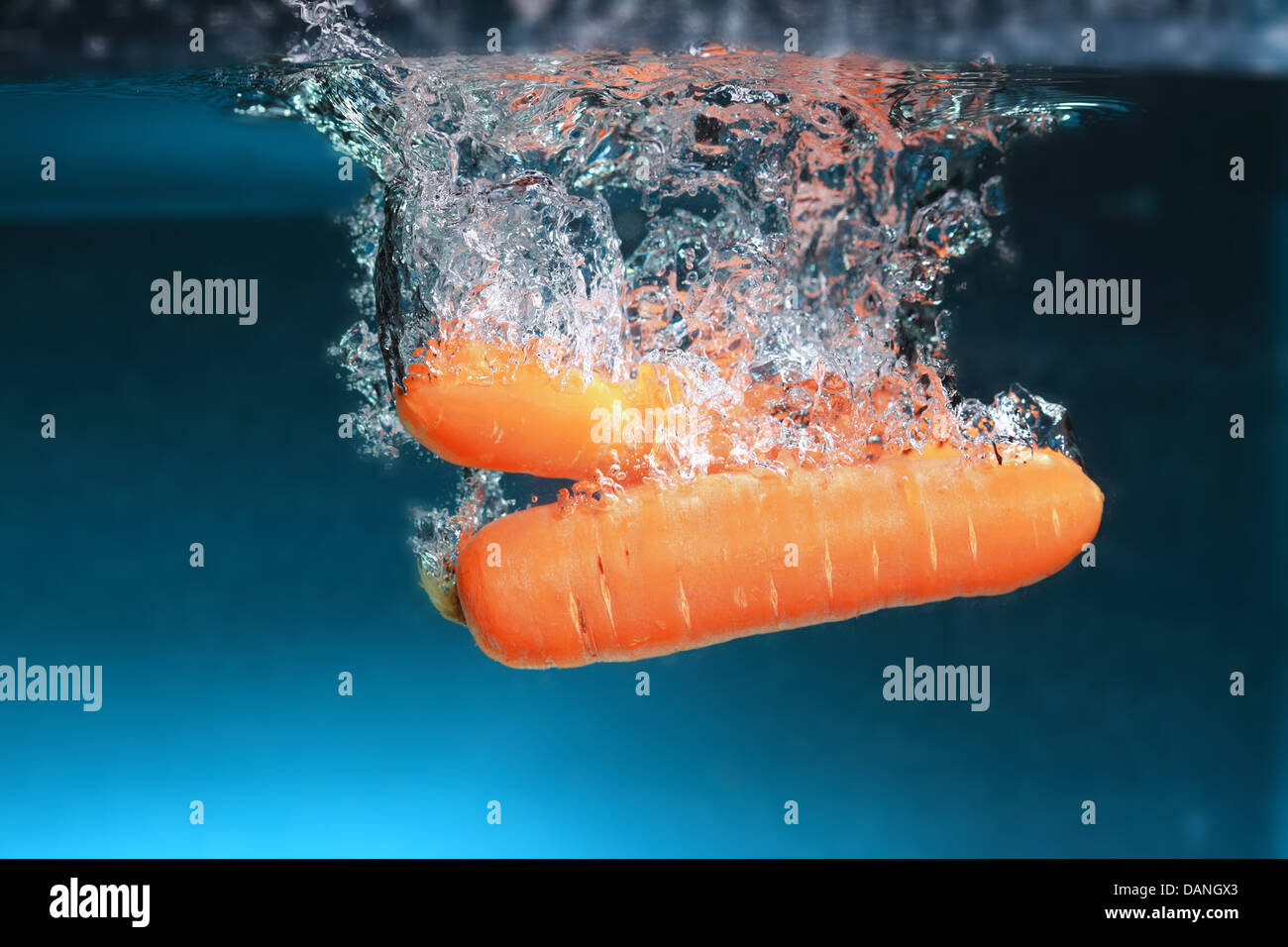 Carrot in the water splash over blue background. Healthy food and ...