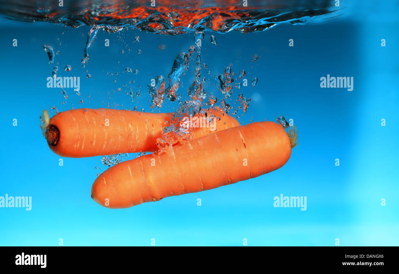 Carrot in the water splash over blue background. Healthy food and ...