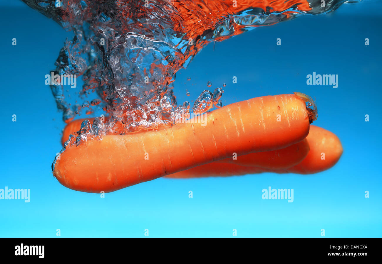 Carrot in the water splash over blue background. Healthy food and ...