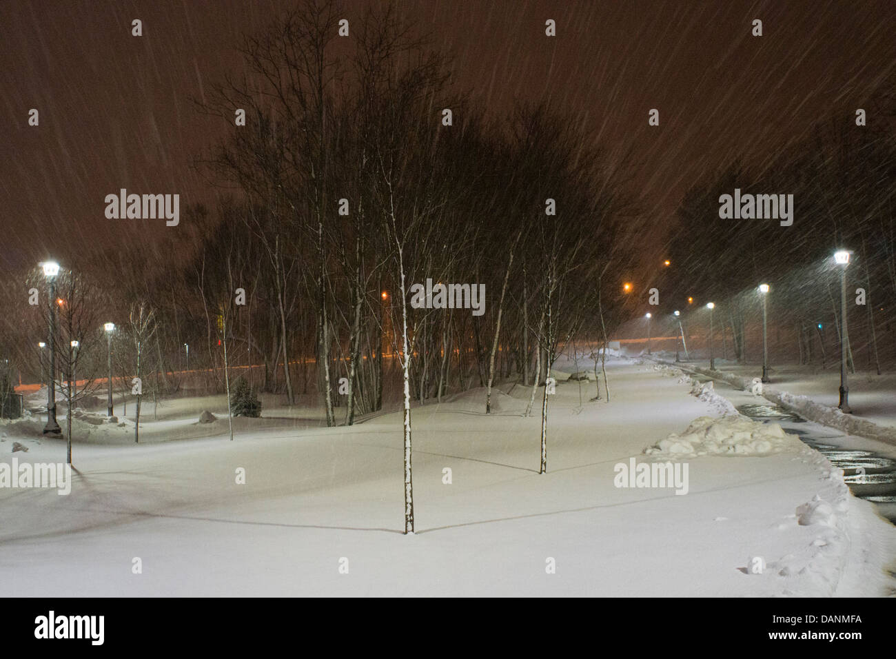 A lit walking path in a small park during a snow storm Stock Photo - Alamy