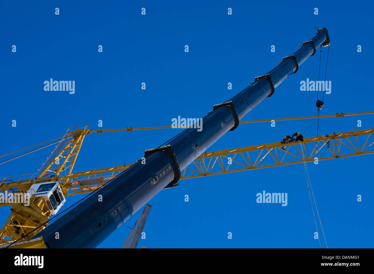 The boom of a tower crane is lifted into position and attached using ...