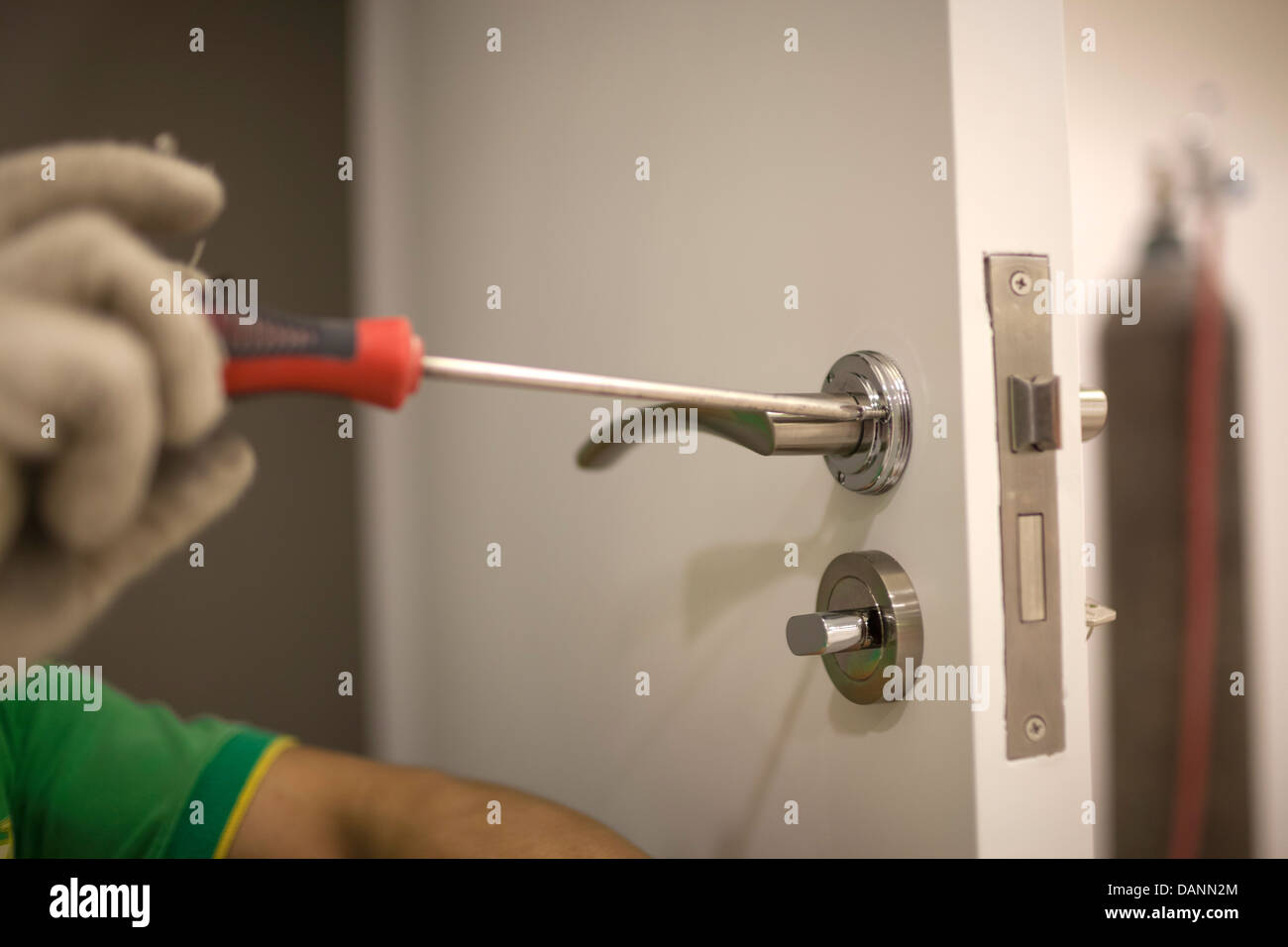 workers are installing a door lock with a screwdriver Stock Photo - Alamy