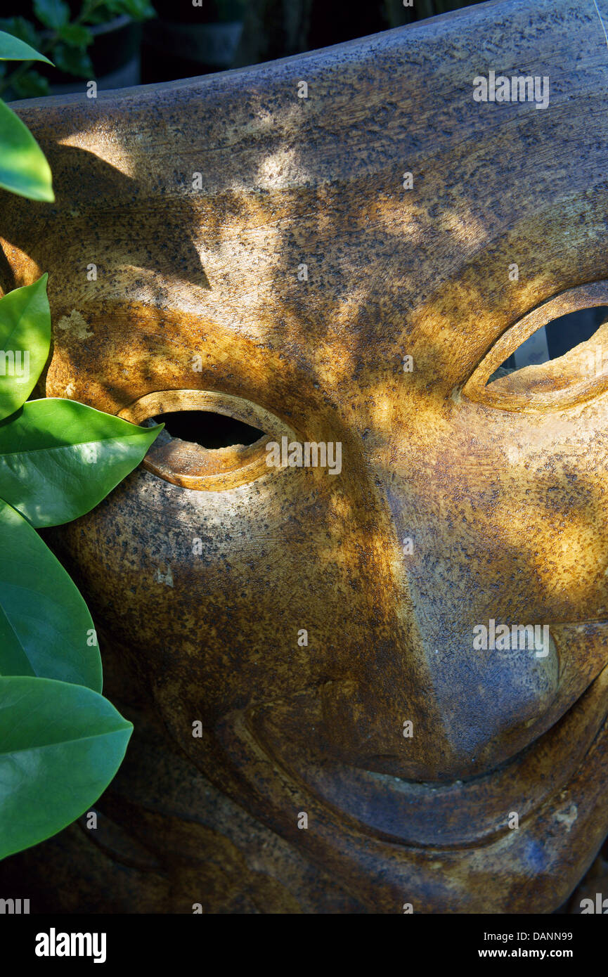 Smiling ceramic mask being used as a garden decoration Stock Photo - Alamy