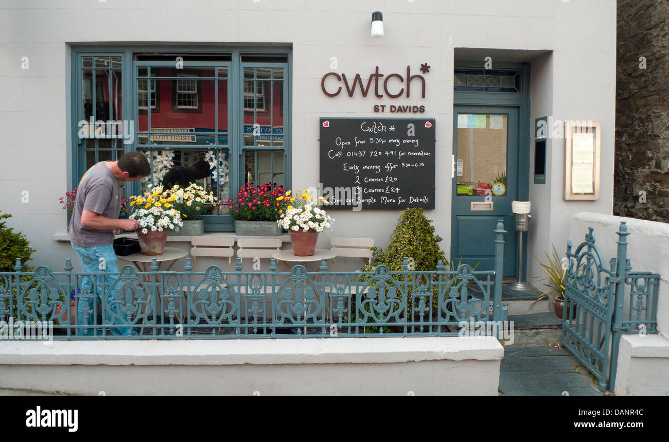 A man arranging flower display in summer outside Cwtch Welsh restaurant ...