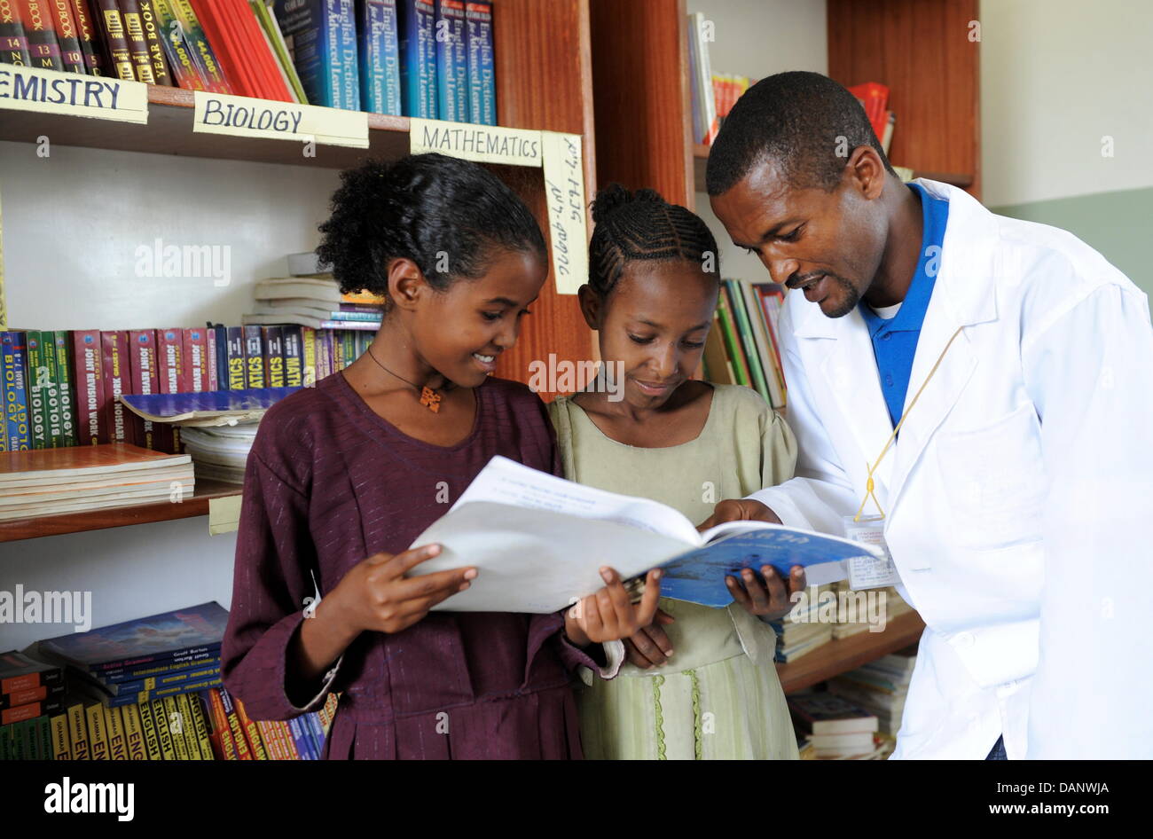 Two pupils and a teacher look at a school book in Dim Dim, Ethiopia, 26 ...