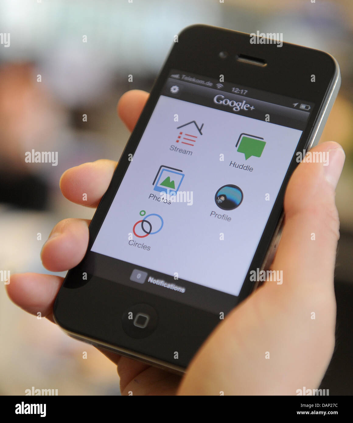 The user interface of Google+ is visible on the display of an iPhone 4 ...