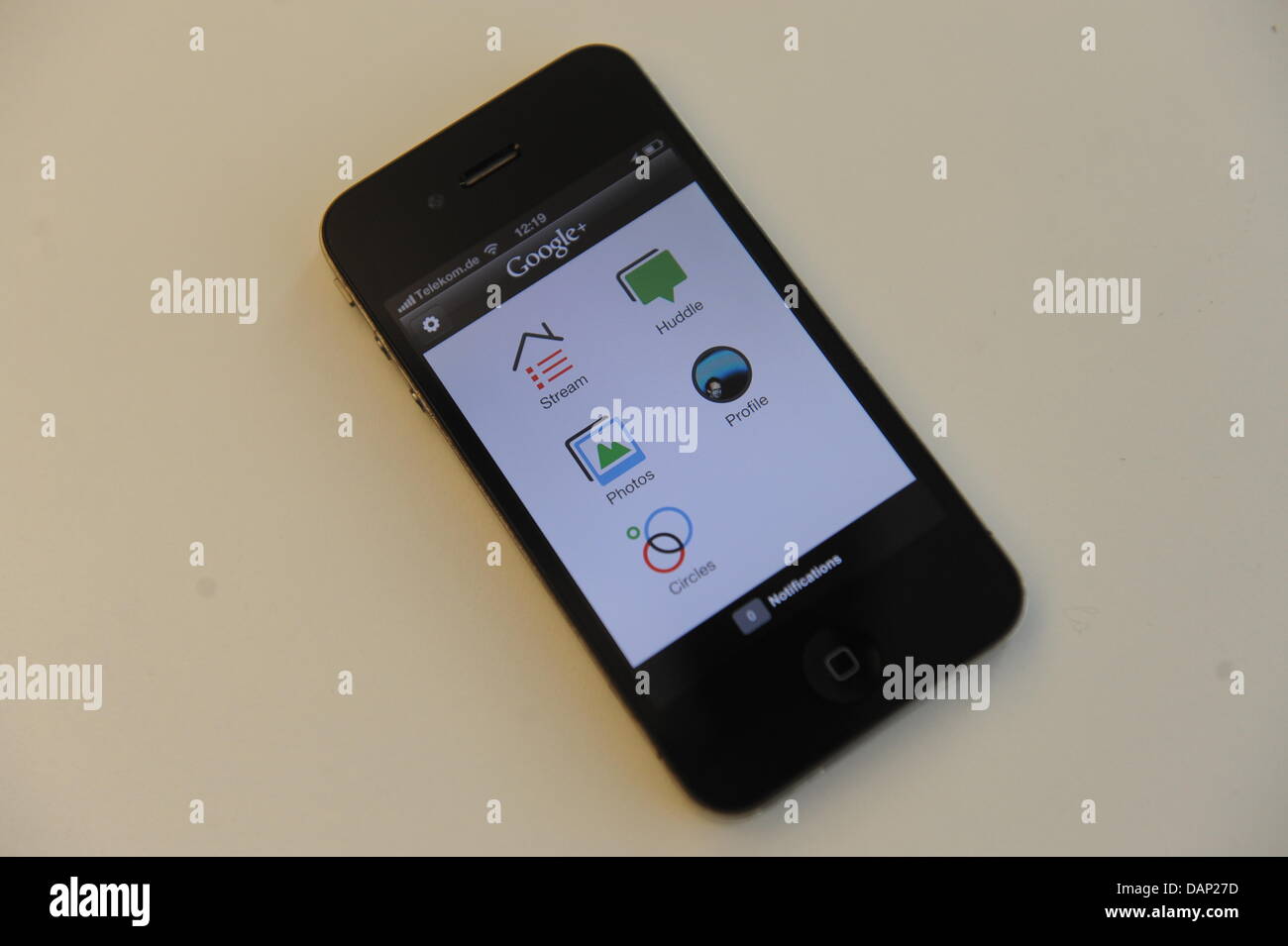 The user interface of Google+ is visible on the display of an iPhone 4 ...