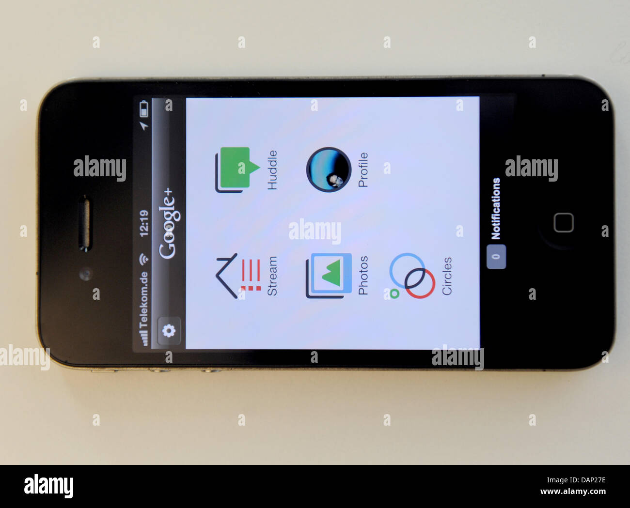 The user interface of Google+ is visible on the display of an iPhone 4 ...