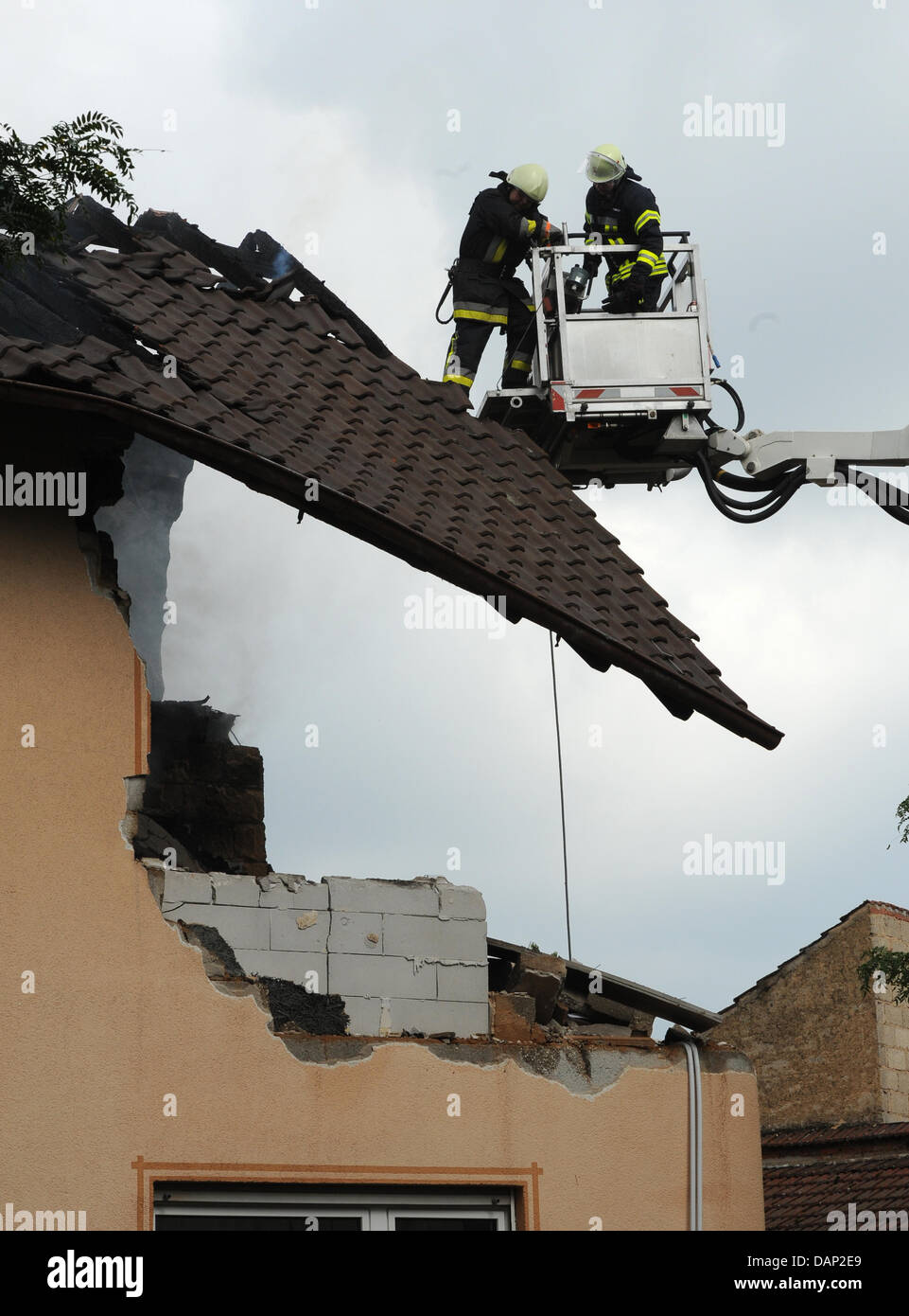A firefighter stands on the roof of a house, damaged by an explosion in ...