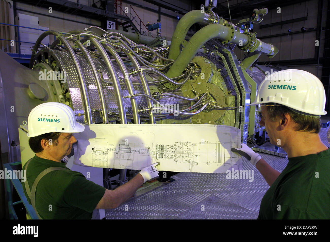 Employees of a Siemens gas turbine plant check the construction drawing ...