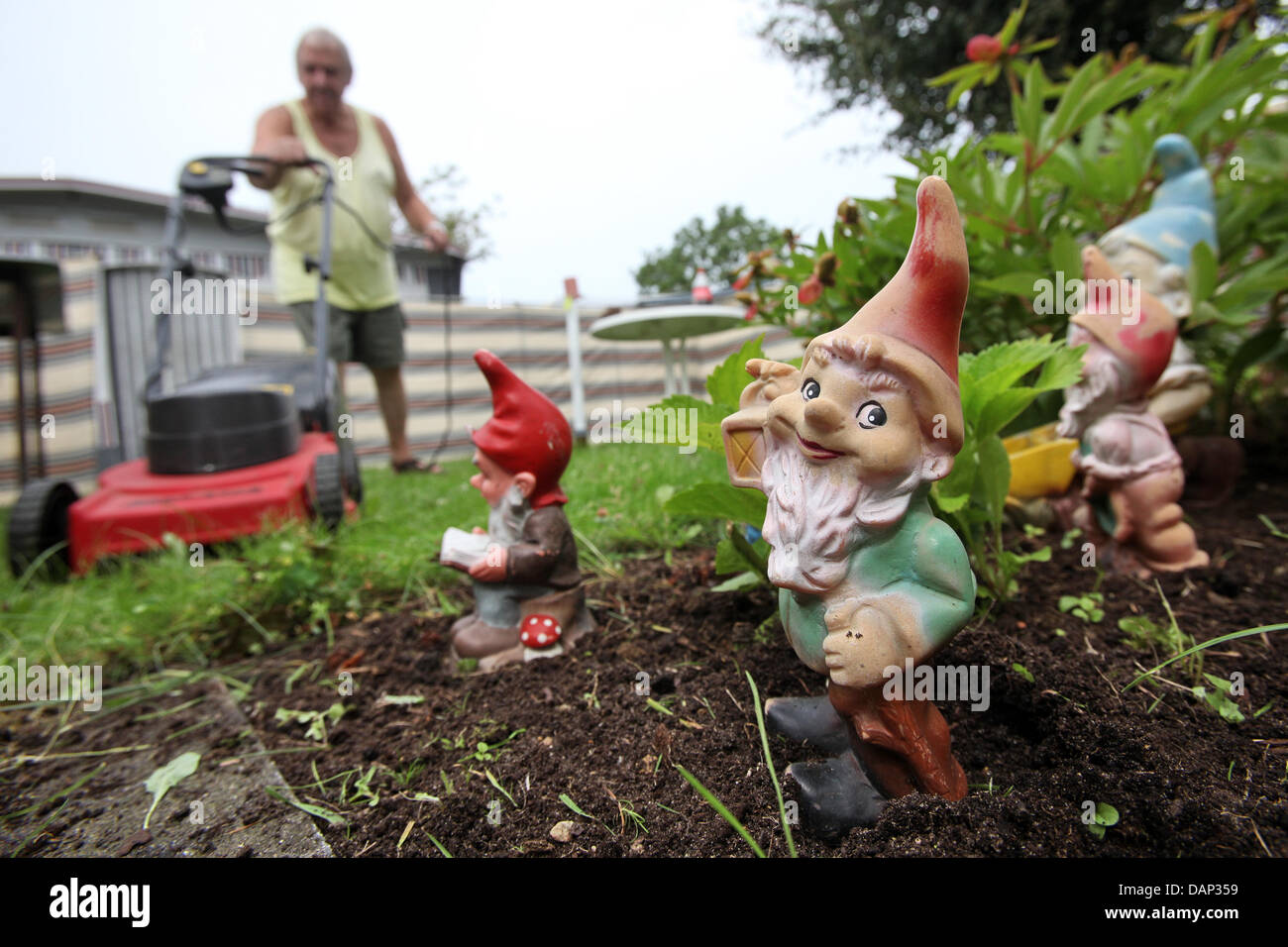 Garden gnomes are situated in a garden in front of the caravan of ...