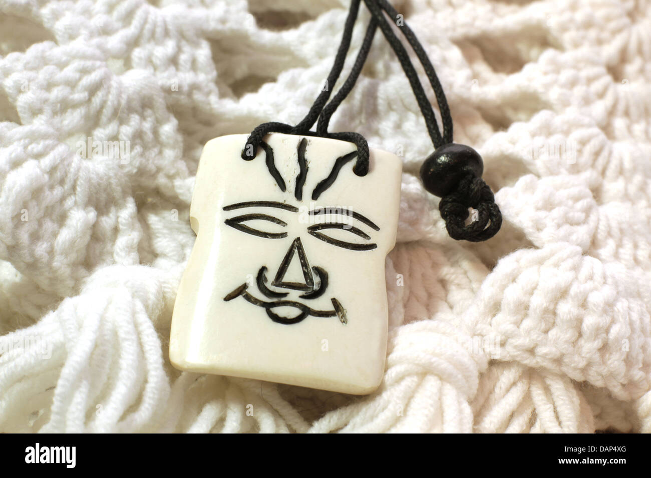 ivory african amulet on knitted white scarf Stock Photo - Alamy