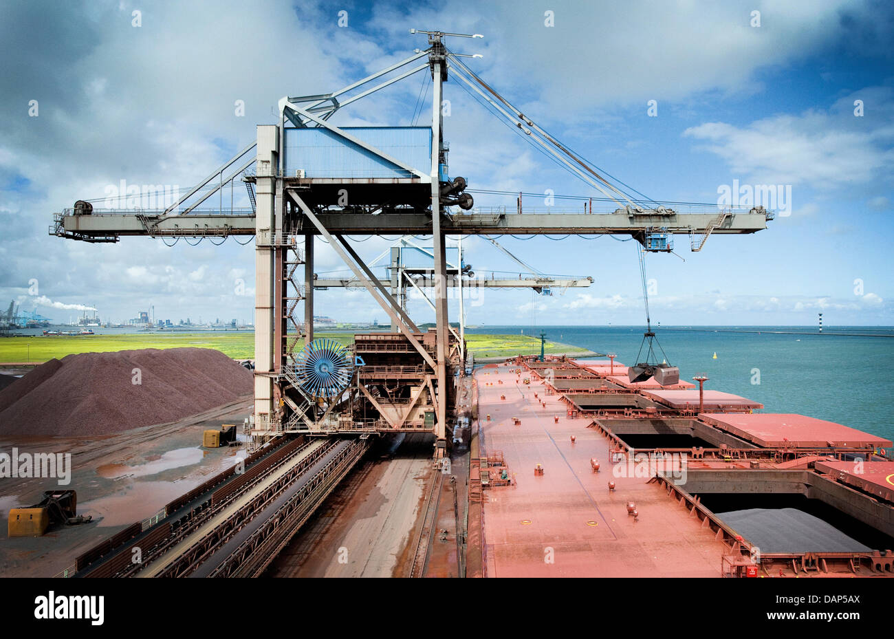 Employees unload iron ore from a cargo ship with with the help of a ...