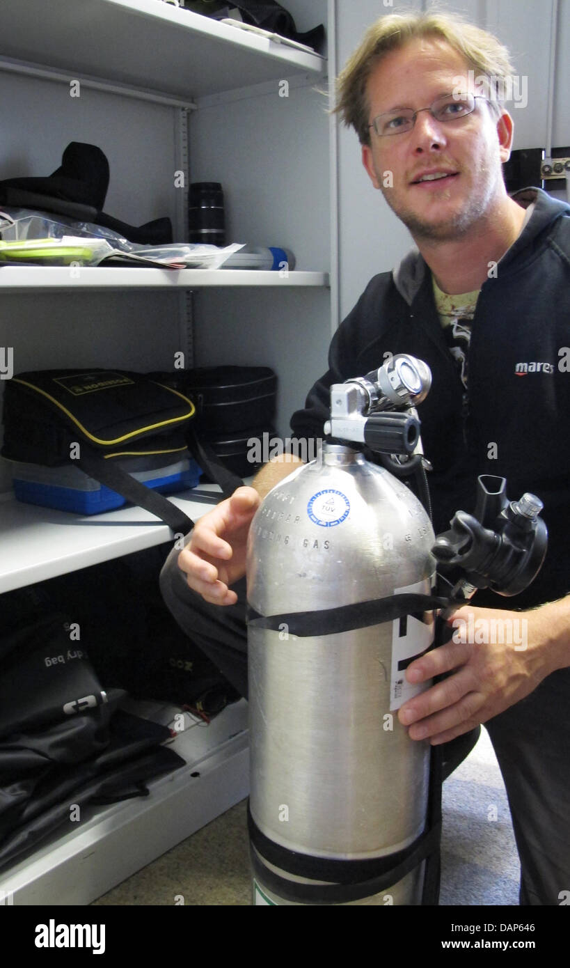 Scientist Florian Huber stands in front of his equipment shelve at the ...