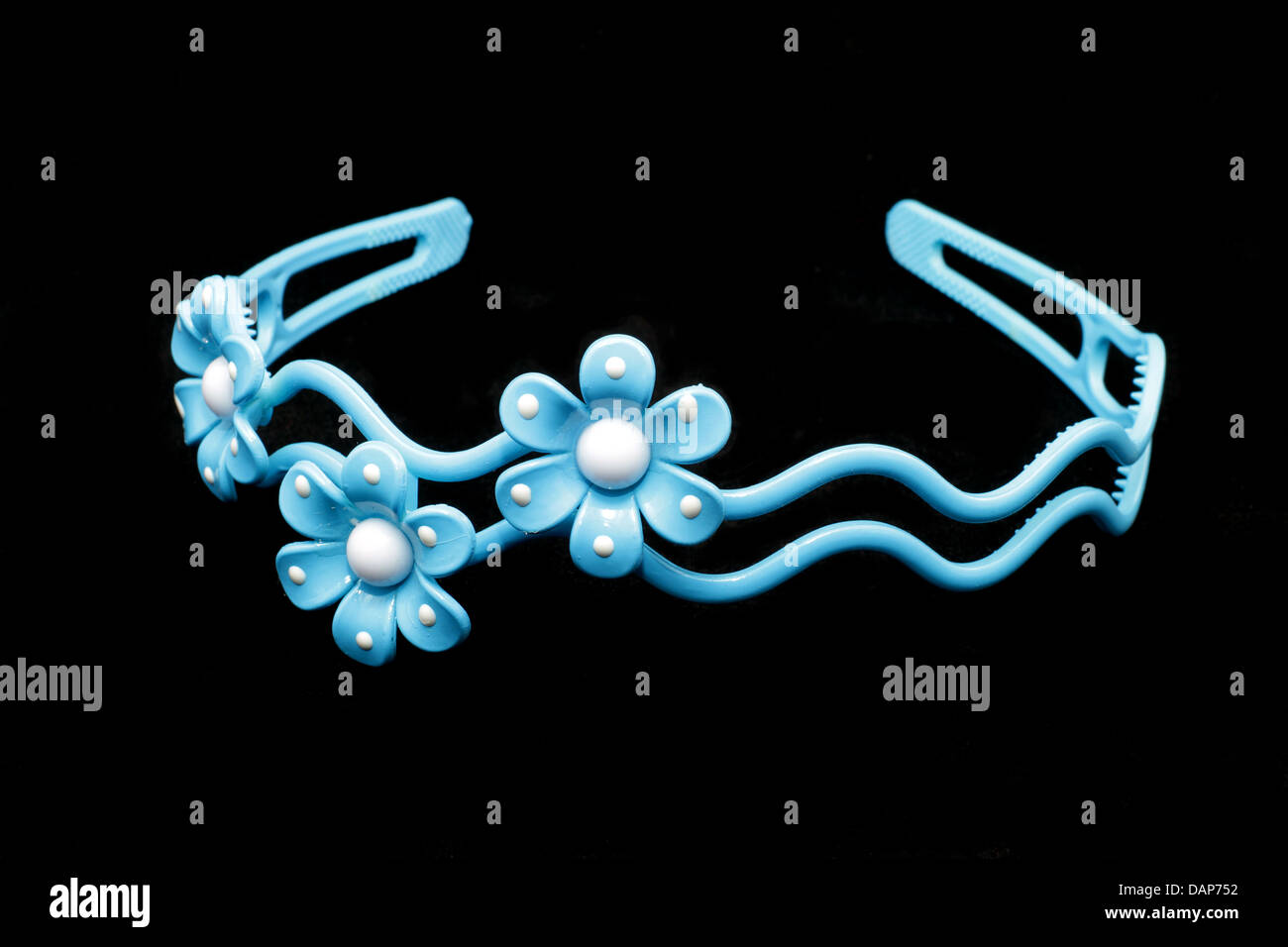 Blue plastic hair band with three flowers on black background Stock ...