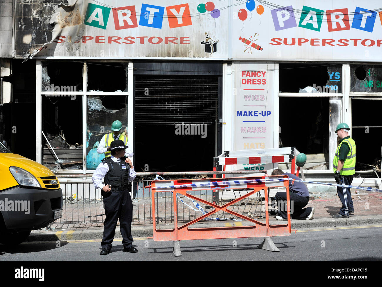 A police officer secures a burnt out shop after riots in Clapham ...