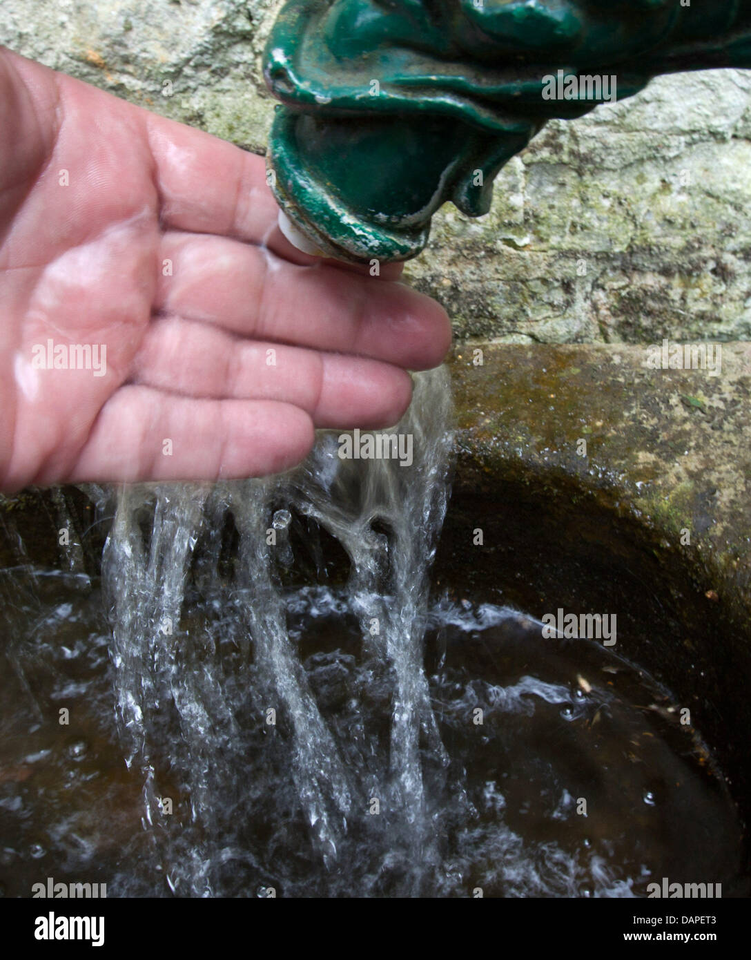 A hand is held in running water under the fountain where the healing ...