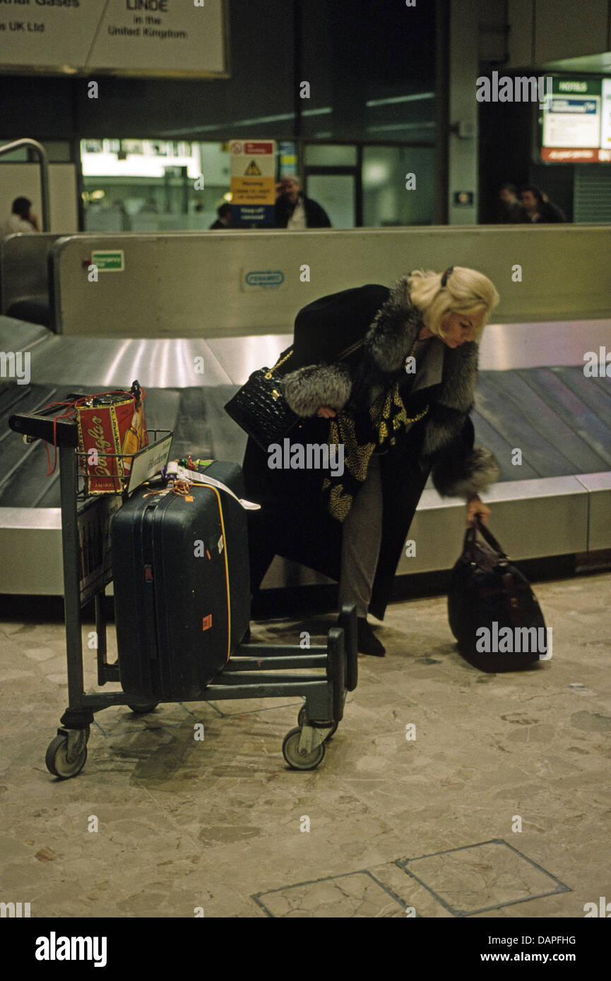 woman in airport baggage claim taking luggage off a terminal Stock ...
