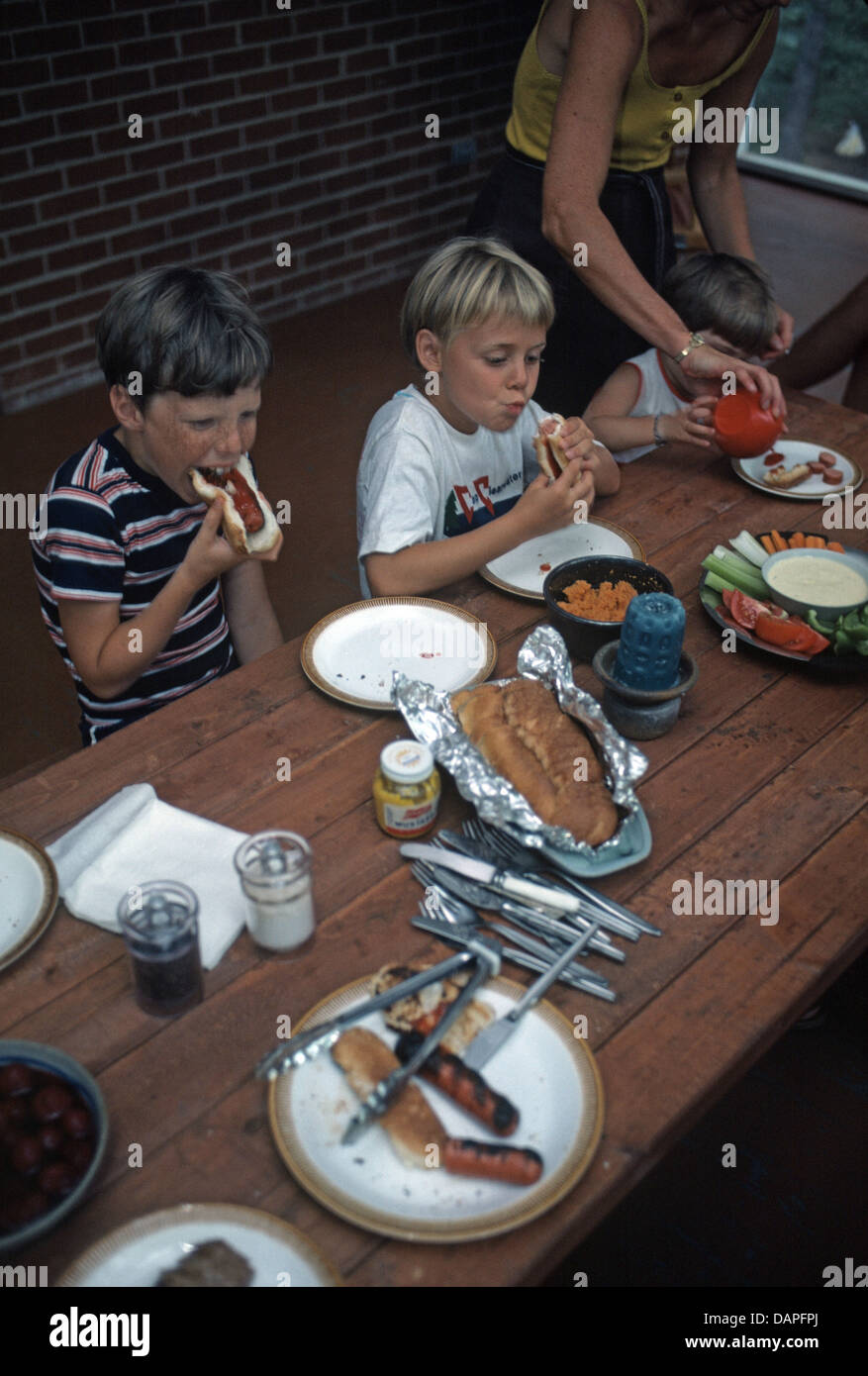 children's party kids eating hot dogs at outdoor table Stock Photo - Alamy