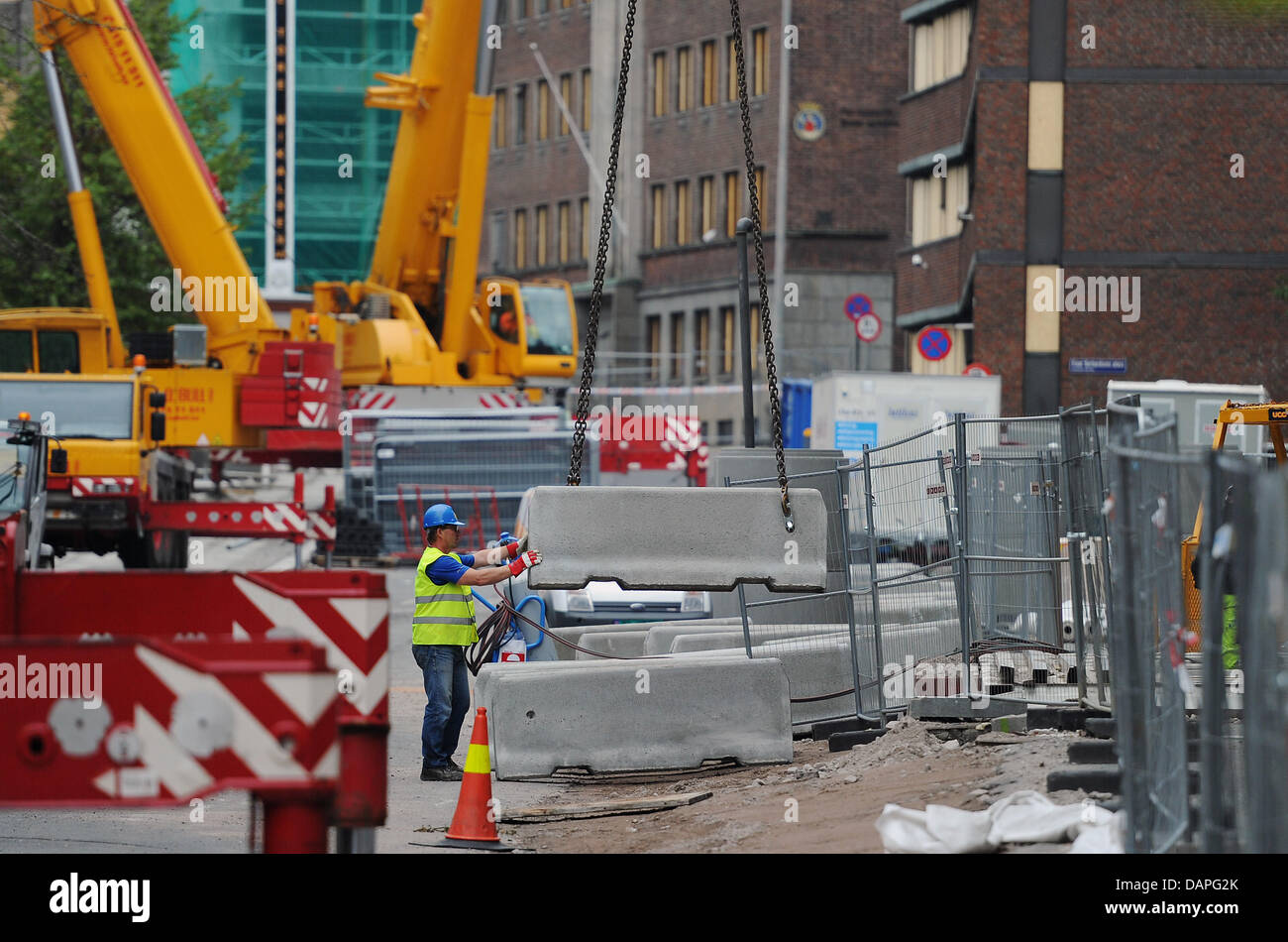Construction workers are pictured at the site of the attacks in Oslo ...