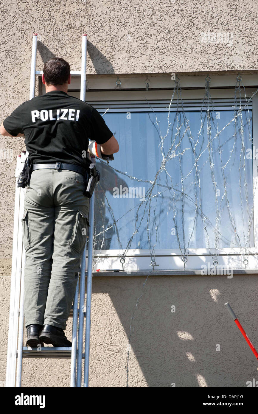 Police officers remove a barbed wire from a window of a flat in Hamburg ...