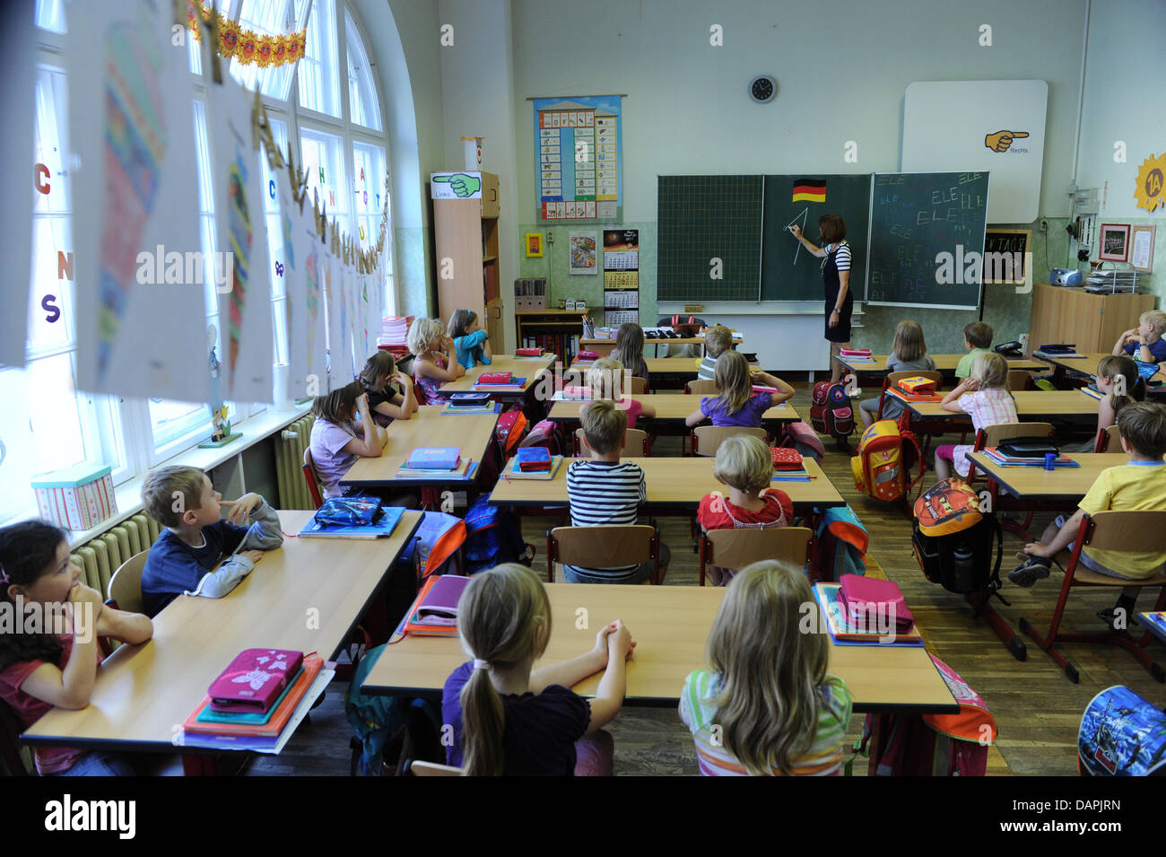 A class of first-graders sit in a lesson as their teacher explains how ...