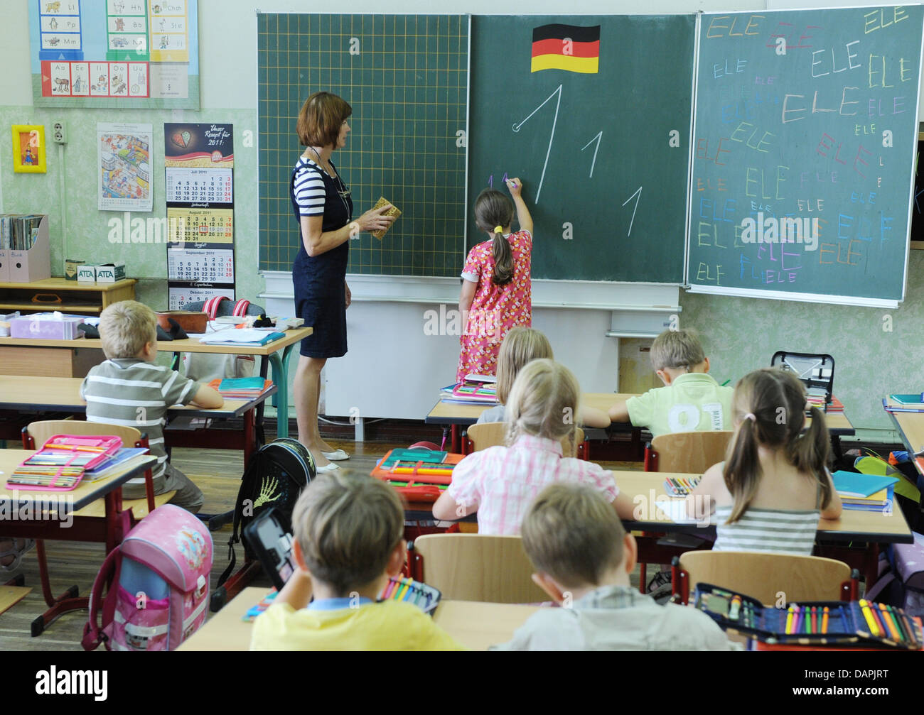 A class teacher instructs a schoolgirl how to write the number '1' on a ...