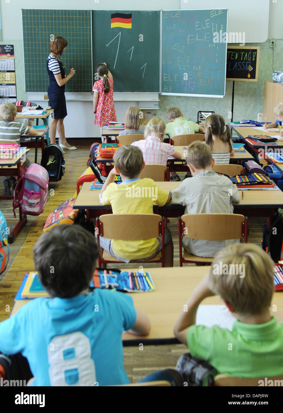 A class teacher instructs a schoolgirl how to write the number '1' on a ...
