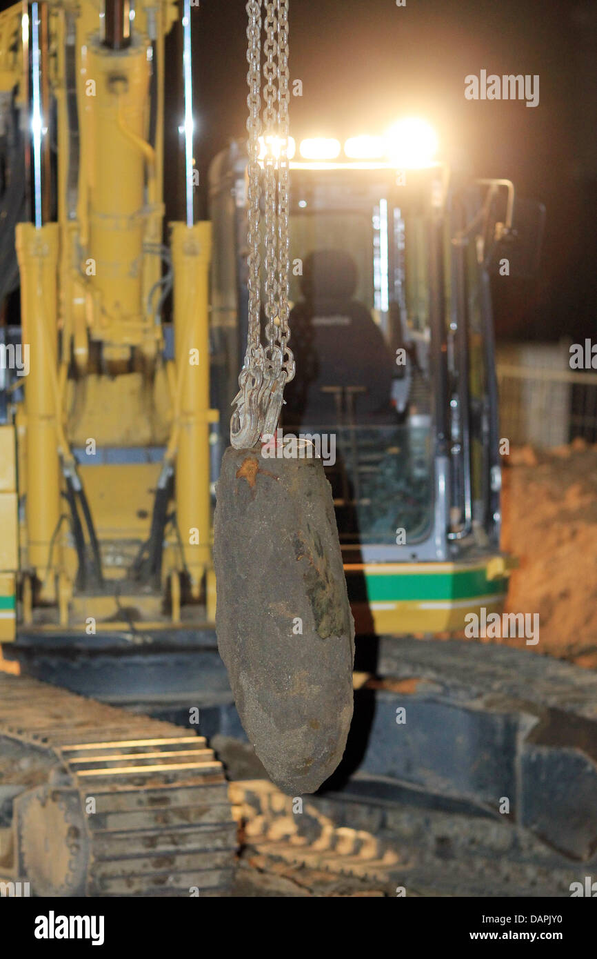 Specialists from the bomb disposal unit lift a World War II aerial bomb ...