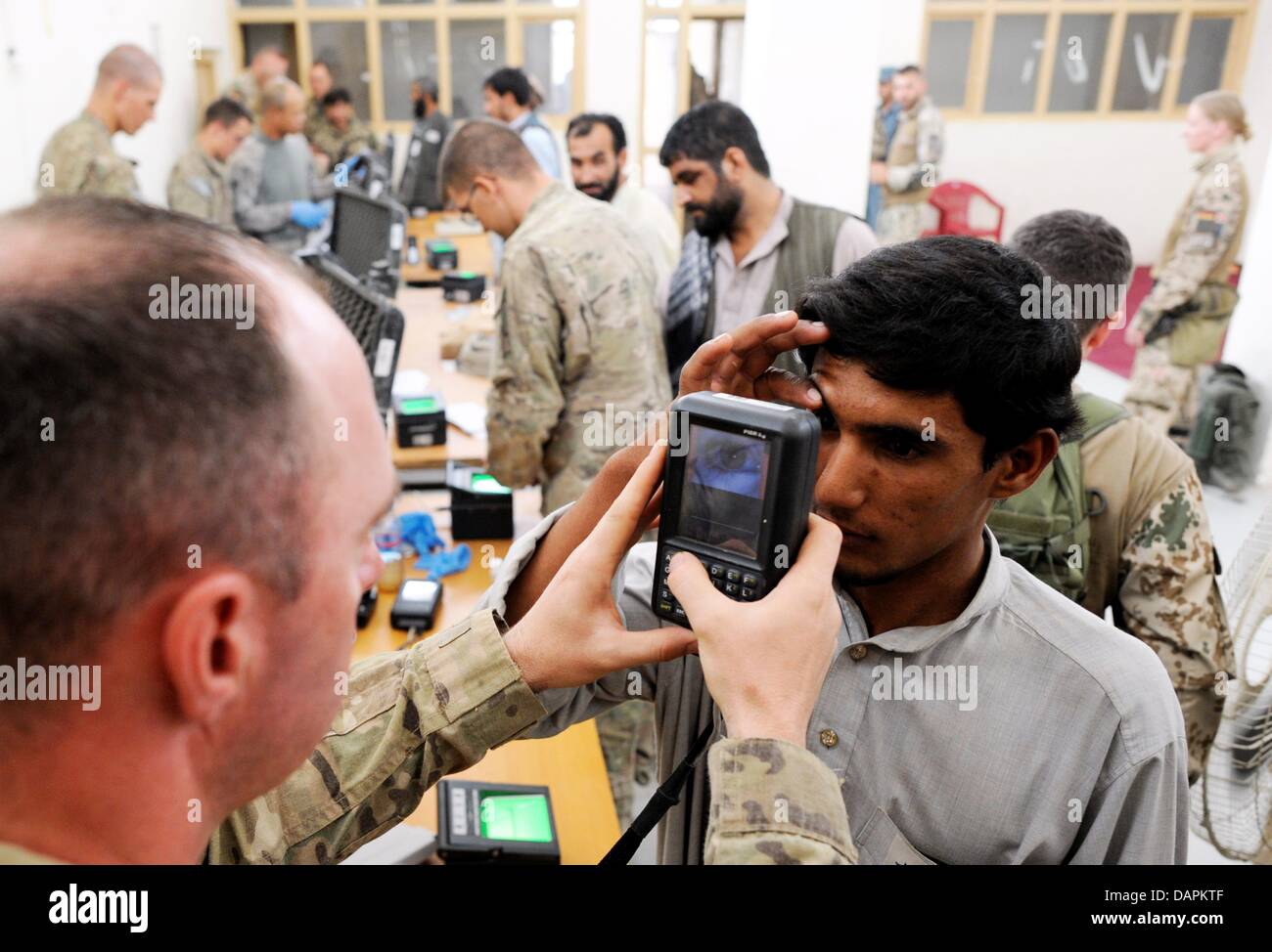 An US ISAF soldier swears in and pays Afghan security men at teh police ...