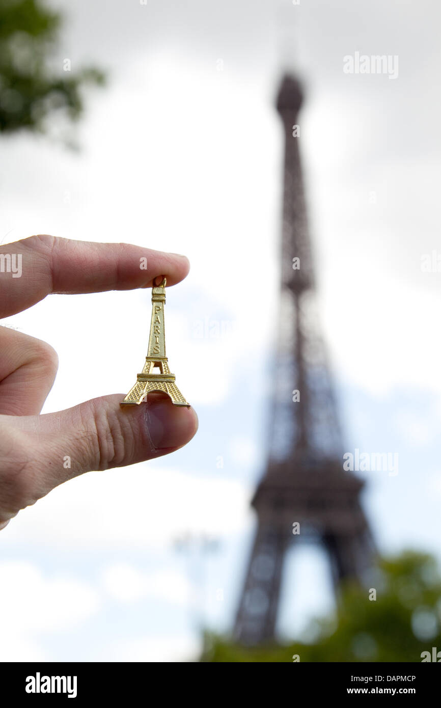 A hand holds a miniature tower next to the actual Eiffel Tower in Paris ... A hand holds a miniature tower next to the actual Eiffel Tower in Paris ...