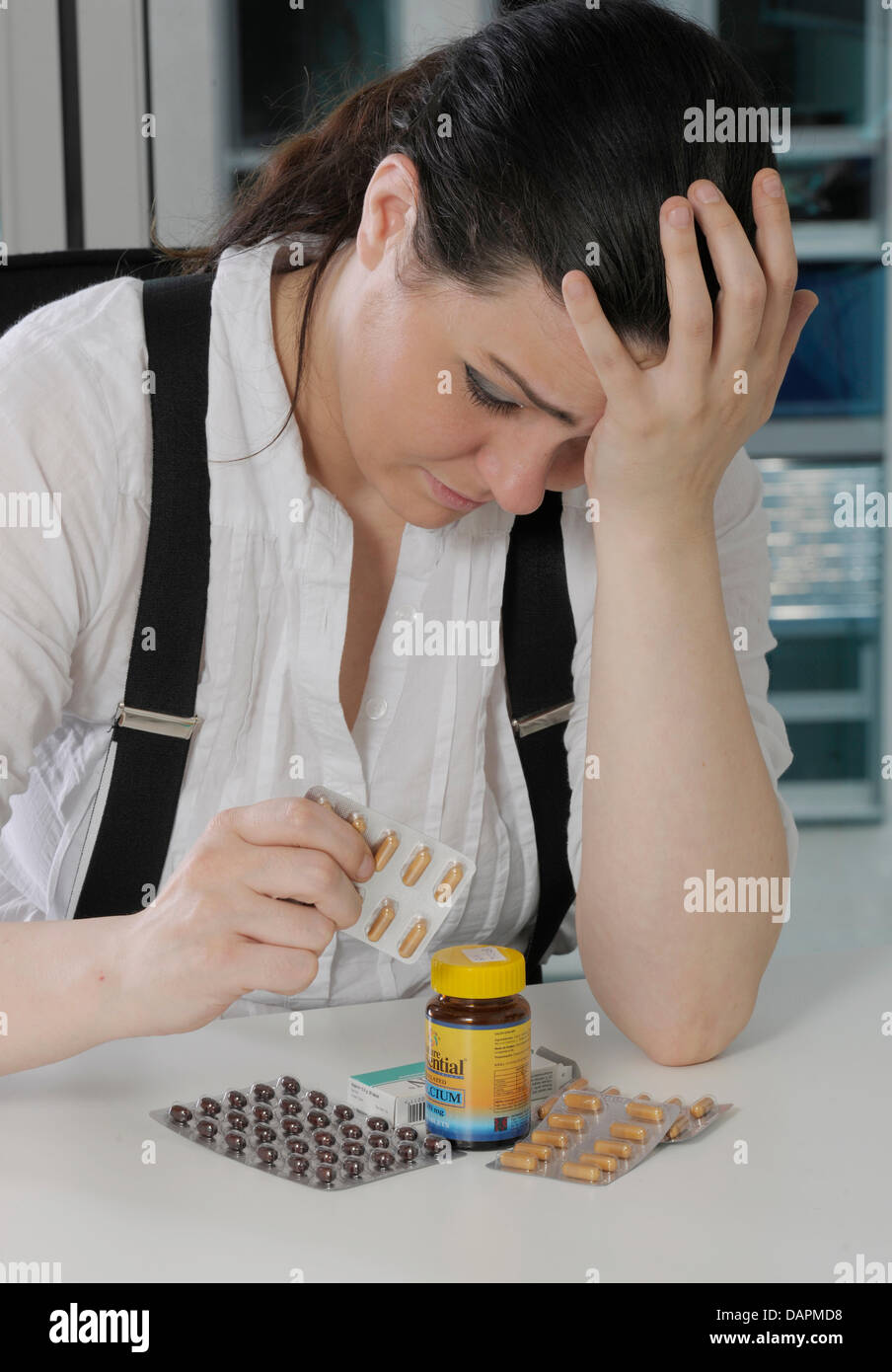 A woman with medication lined up in front of her sits at a table and ...