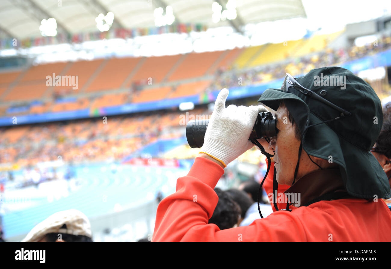 A spectator wearing white gloves watches the scene through binoculars ...