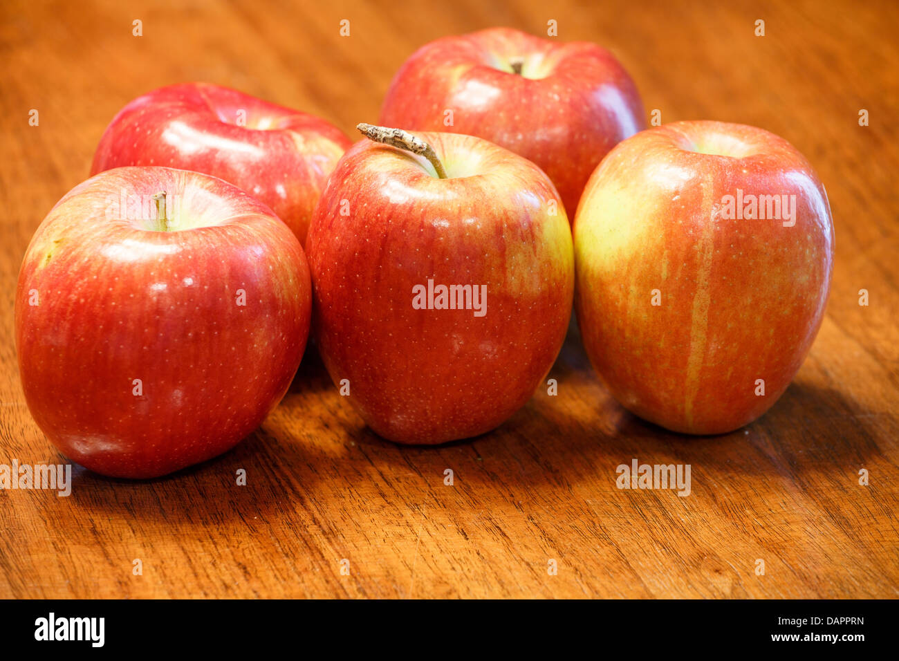 Five red apples on a wood table Stock Photo - Alamy