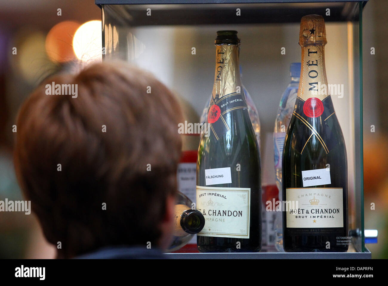 A man looks at an authentic and a fake champagne bottle at the ...