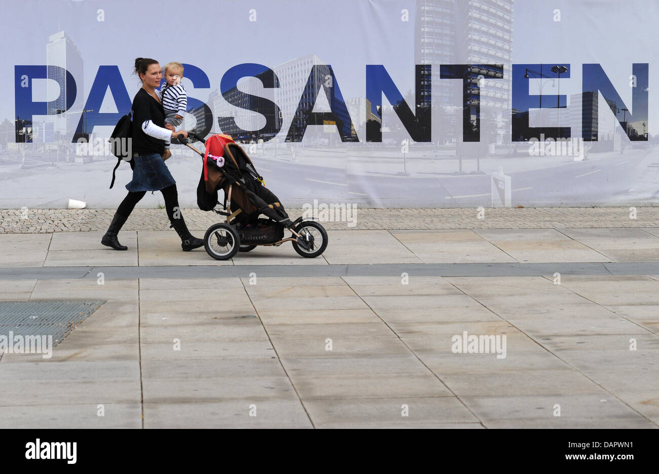 A young woman and her child walk past the writing 'Passanten' ('passers ...