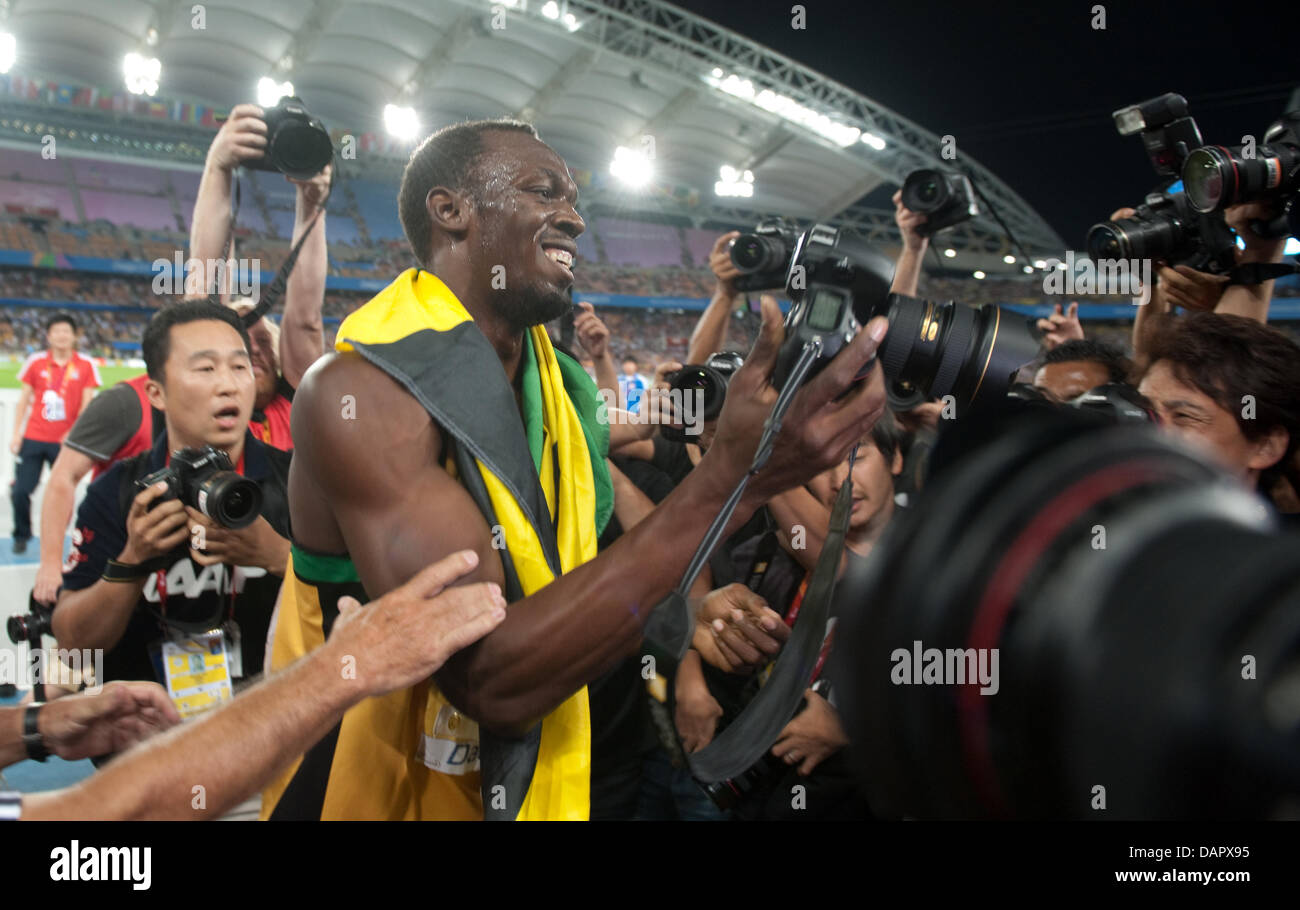 Usain Bolt of Jamaika gives back a loan camera to a photographer after ...