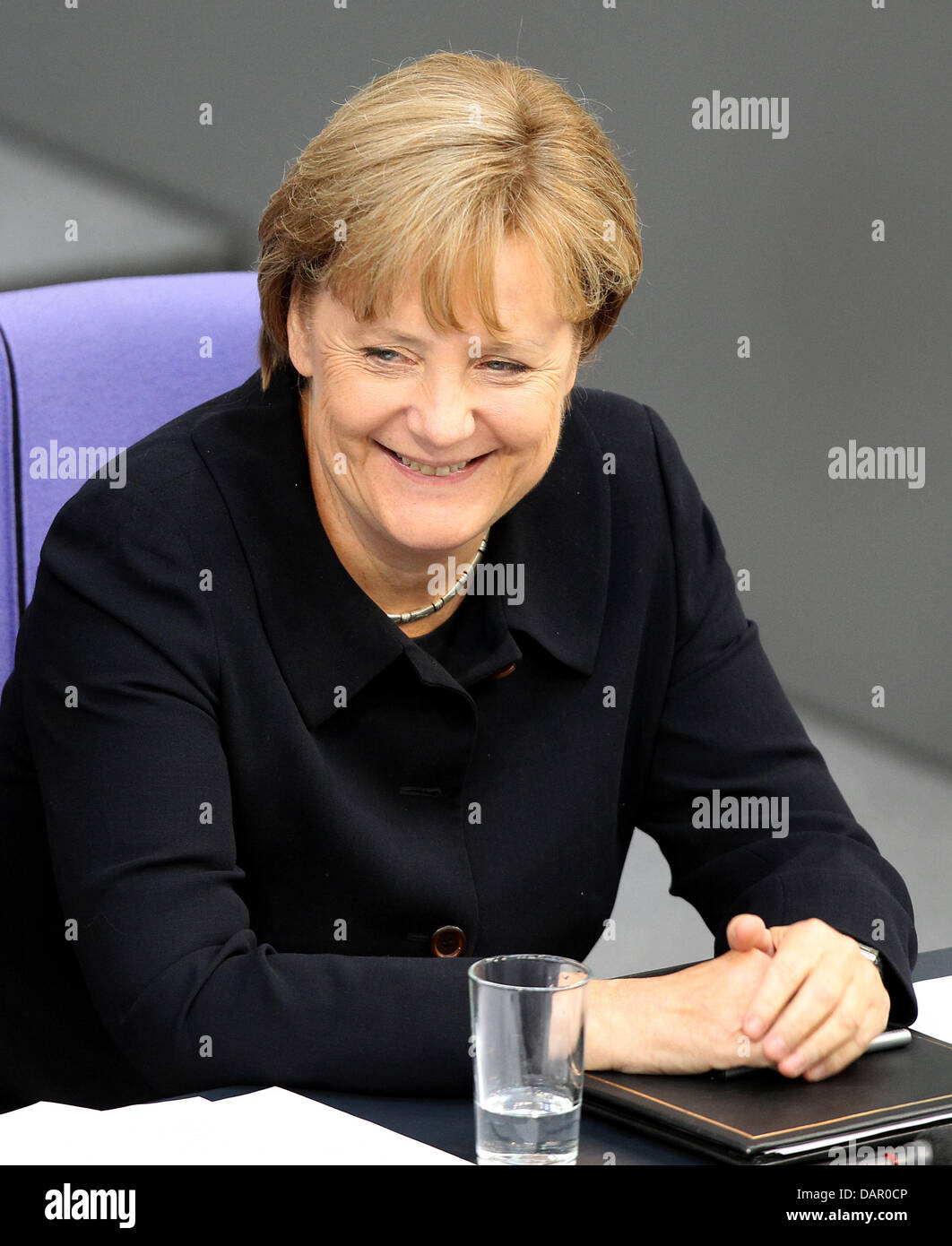 German Chancellor Angela Merkel smiles while sitting on the government ...