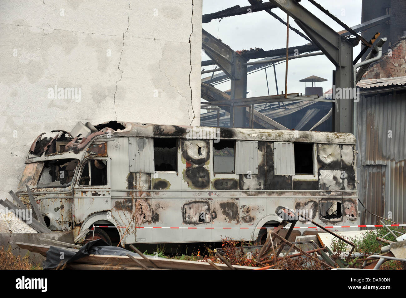 A burned out bus sits in front of a burned down storehouse on a farm in ...