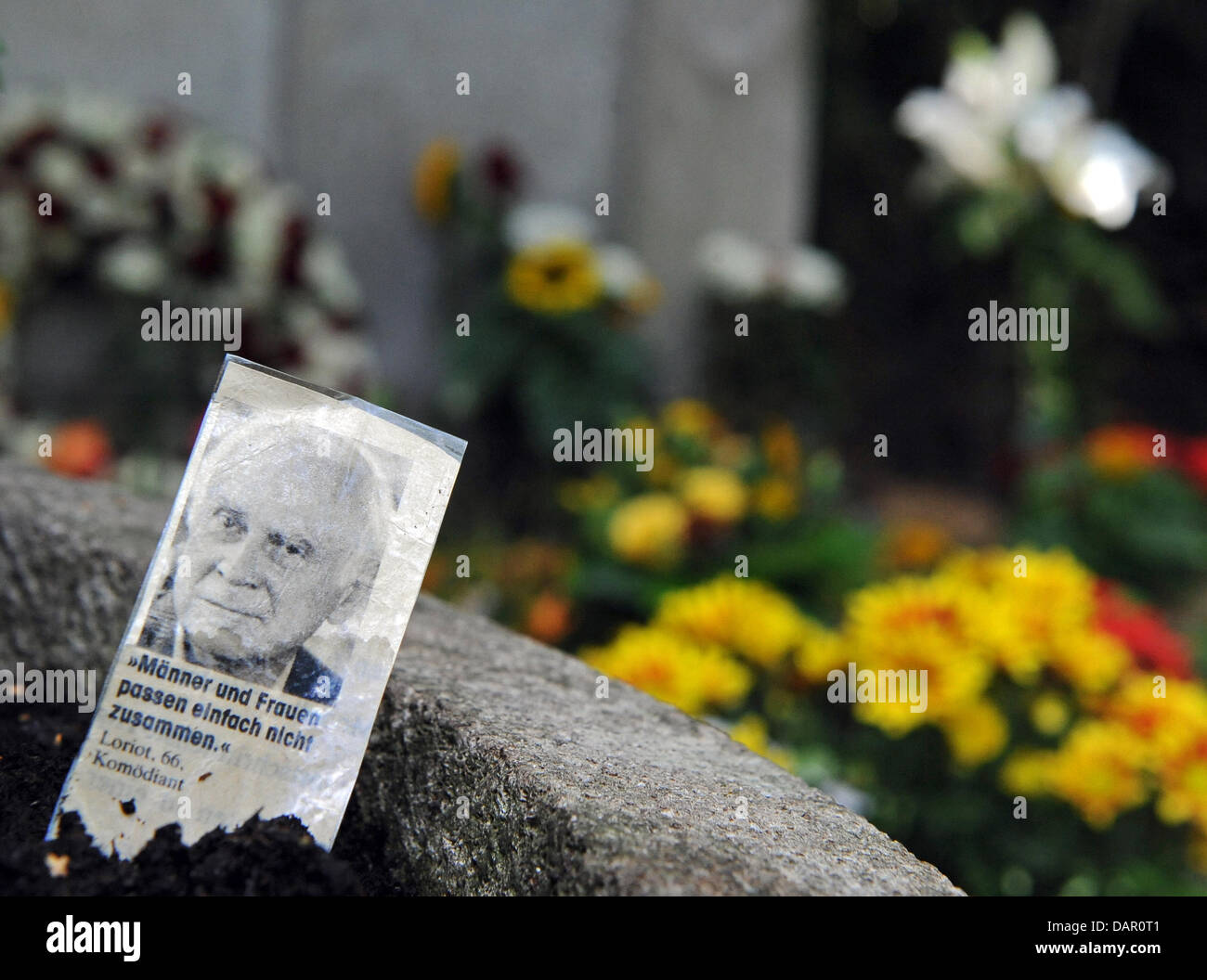Flowers, newspaper clippings and floral wreaths lie on the grave of ...