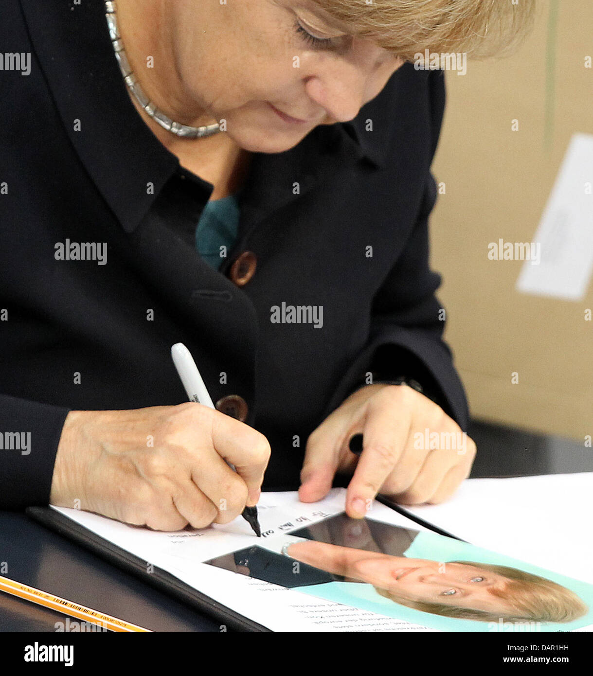 German Chancellor Angela Merkel signs a portrait during the final ...