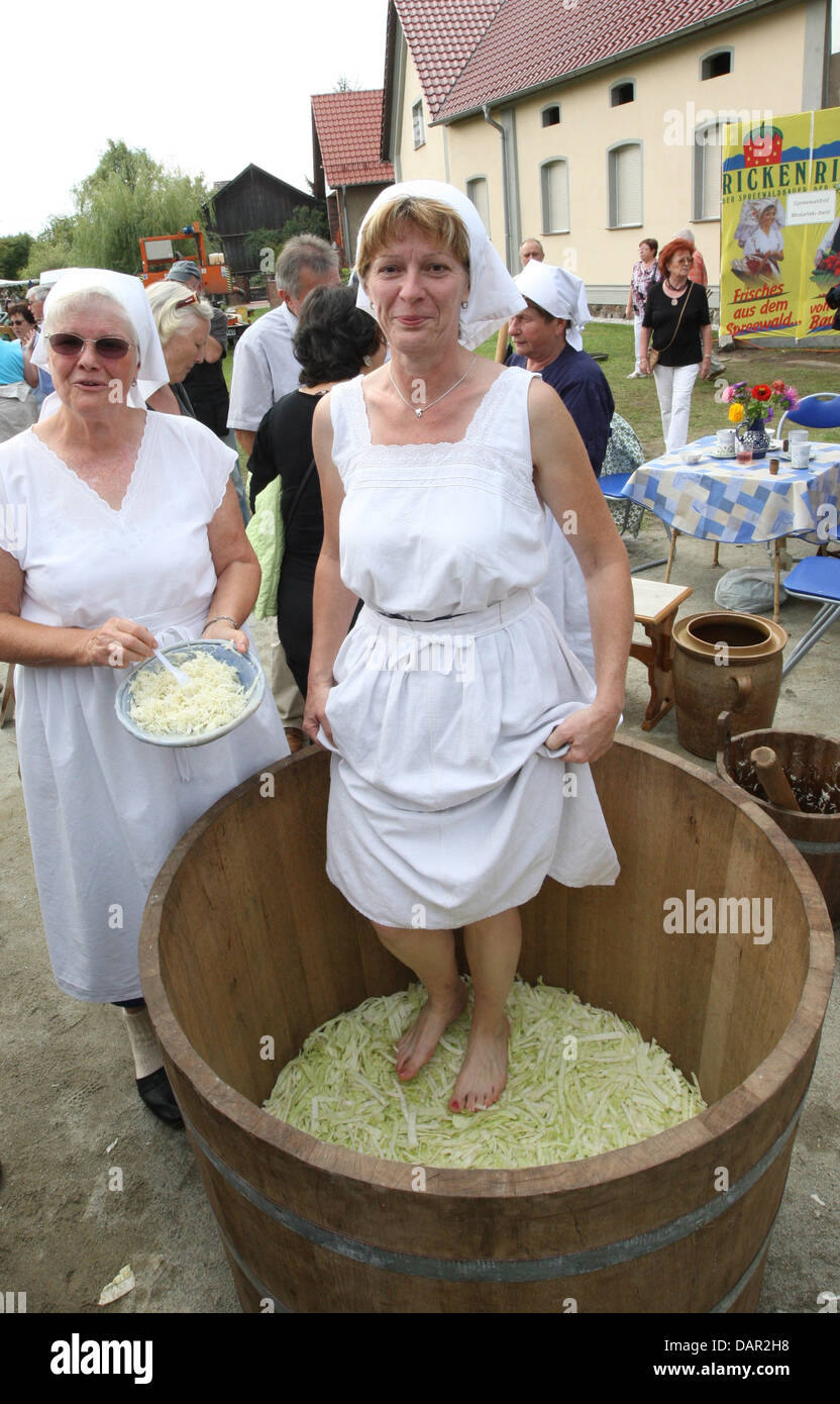 Farmer Petra Mross stamps white cabbage in a wooden barrel, while her ...