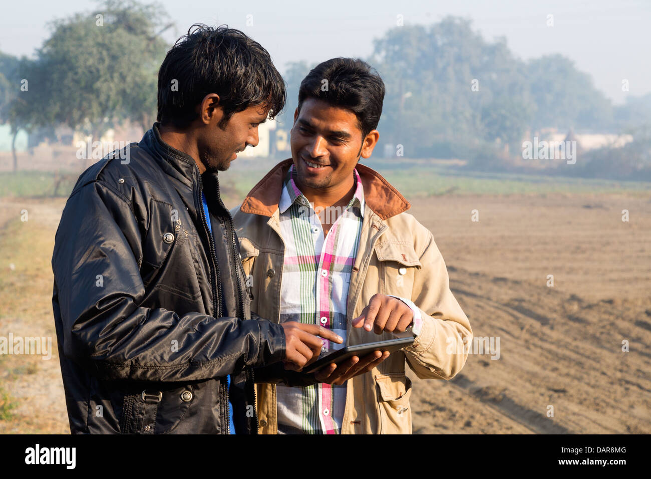 India, Uttar Pradesh, Agra, two young men using tablet device in rural ...