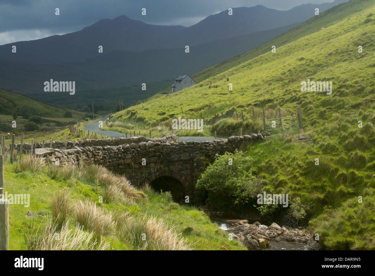 Stream, old stone arched bridge, country road with mountains in ...