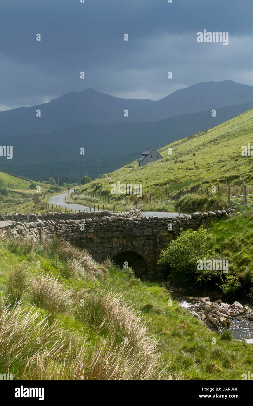 Stream, old stone arched bridge, country road with mountains in ...