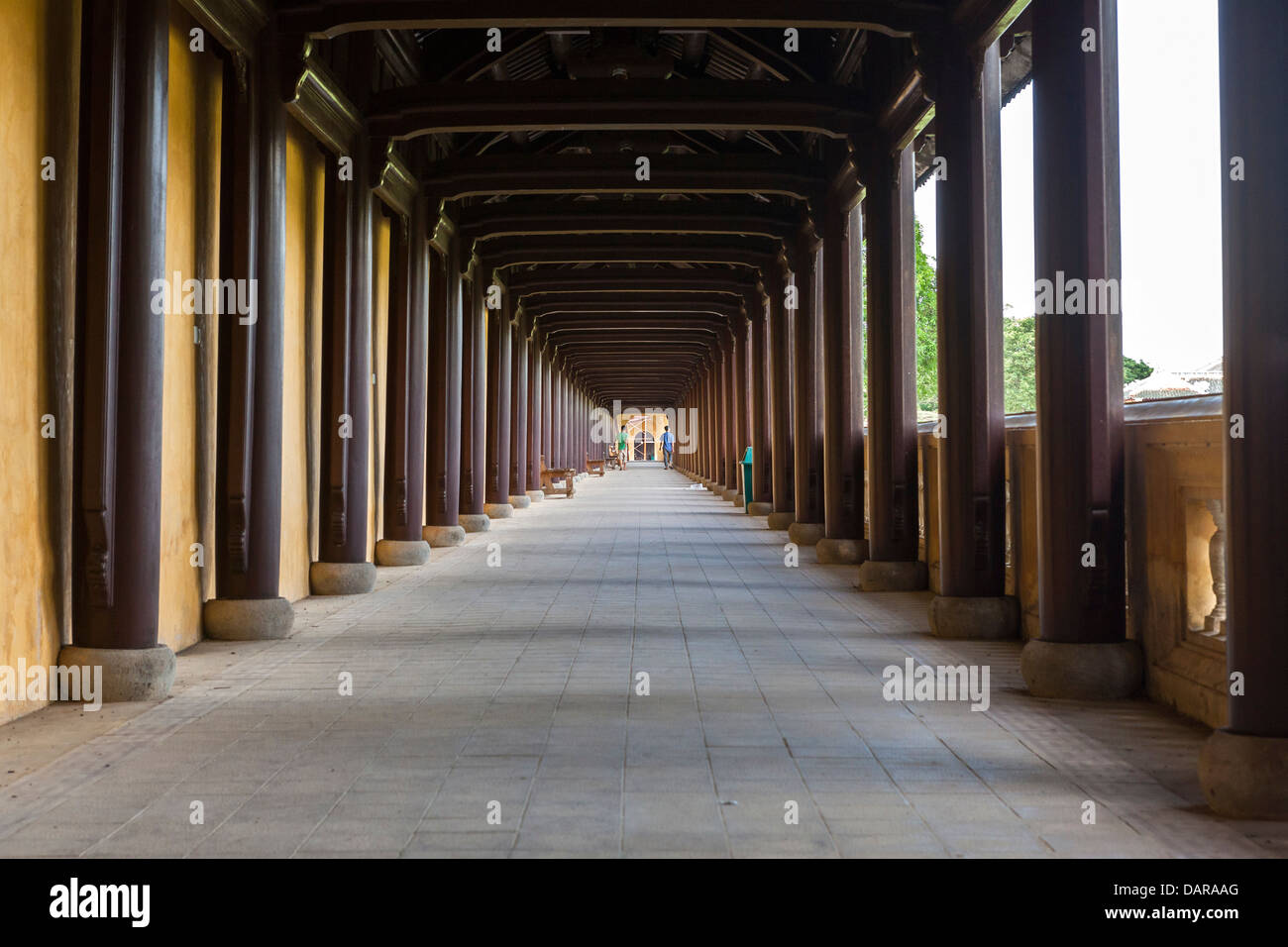 A long outside corridor, with wooden pillars leads into the distance ...