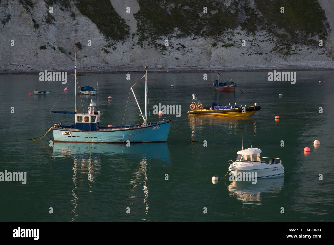 Fishing boats and leisure craft moored below the chalk cliffs of ...