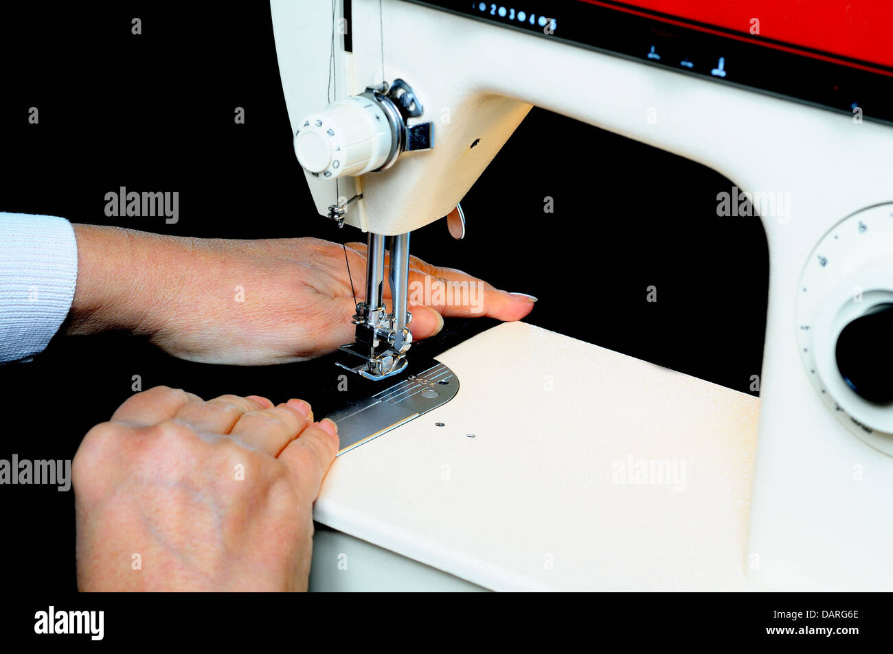Woman using a domestic electric sewing machine to stitch black velvet ...