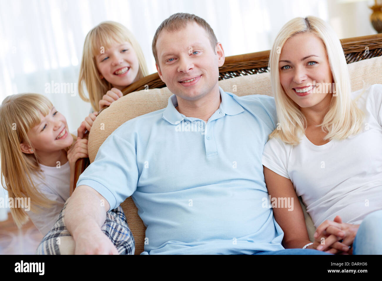 Happy parents looking at camera while their daughters laughing at them ...